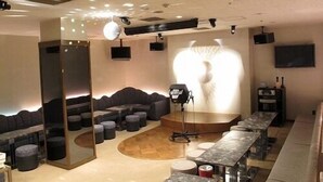 Uma área de estar moderna com um espelho grande, assentos, palco e tela de projeção.