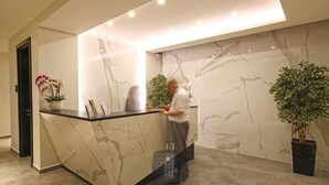 Uma área de recepção moderna com balcão de mármore, plantas em vasos e um design limpo e minimalista.