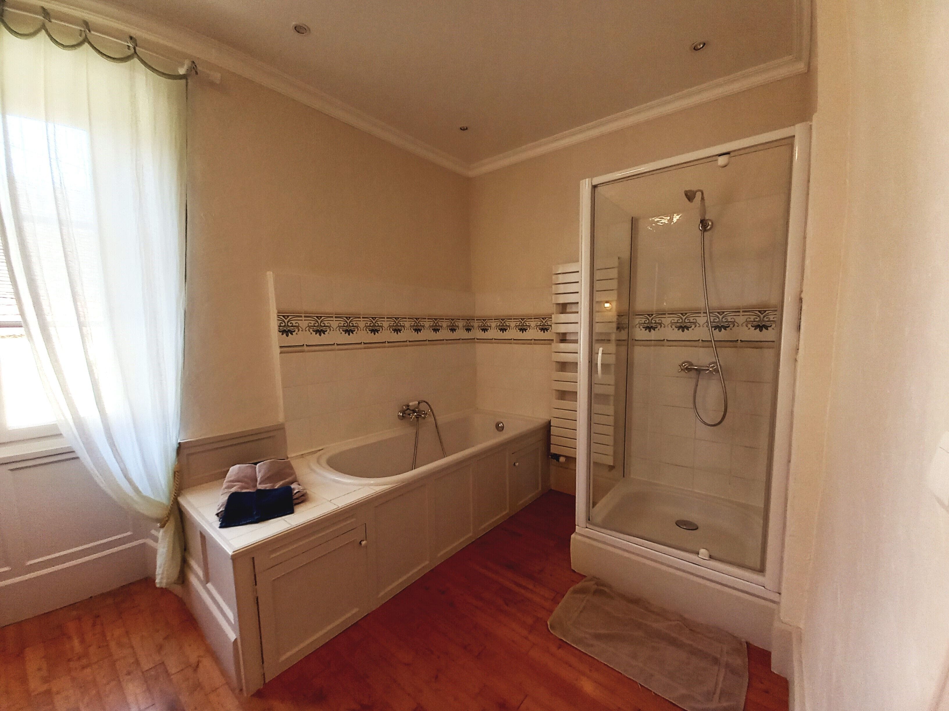 Uma casa de banho com banheira, chuveiro e toucador com porta-toalhas.