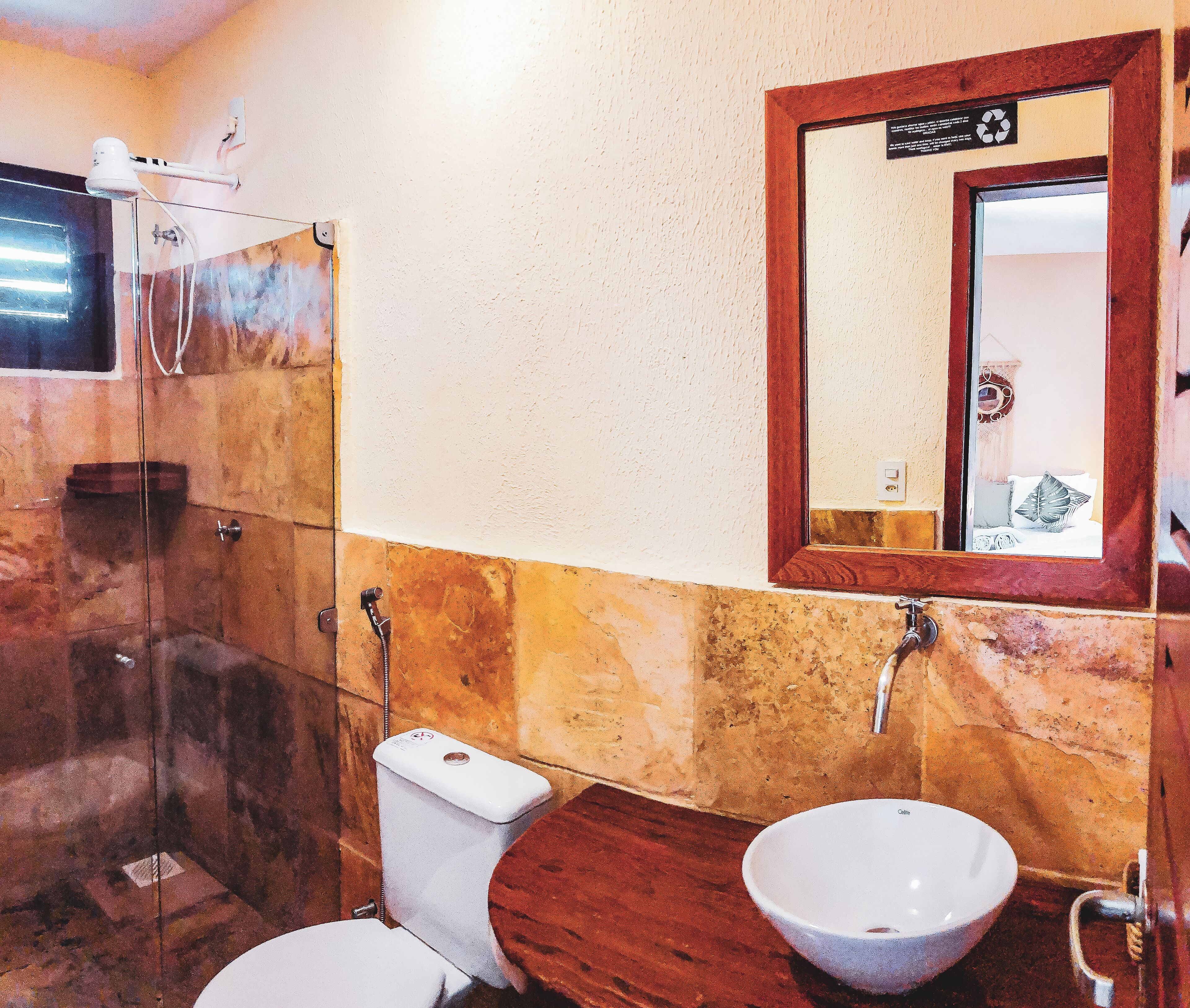 Casa de banho com cabine de duche em vidro, sanita e lavatório com bancada de madeira.
