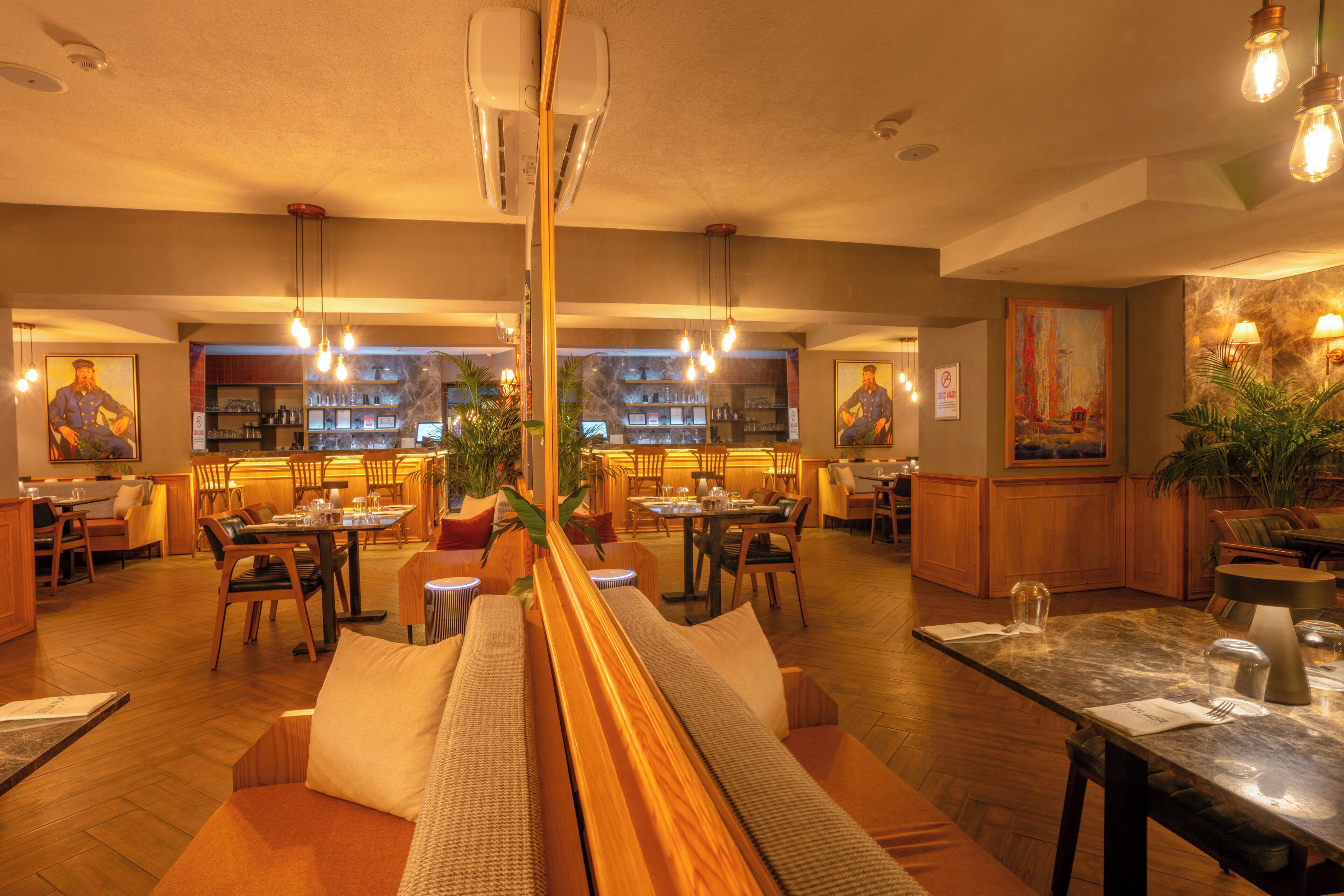 Um restaurante com várias áreas de refeição, mobiliário de madeira e luminárias pendentes.
