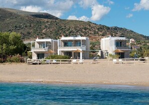 Na praia, areia branca, espreguiçadeiras, guarda-sóis