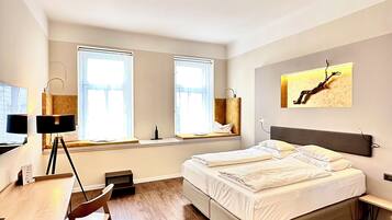 Quarto moderno com uma cama grande, uma escrivaninha e duas janelas.