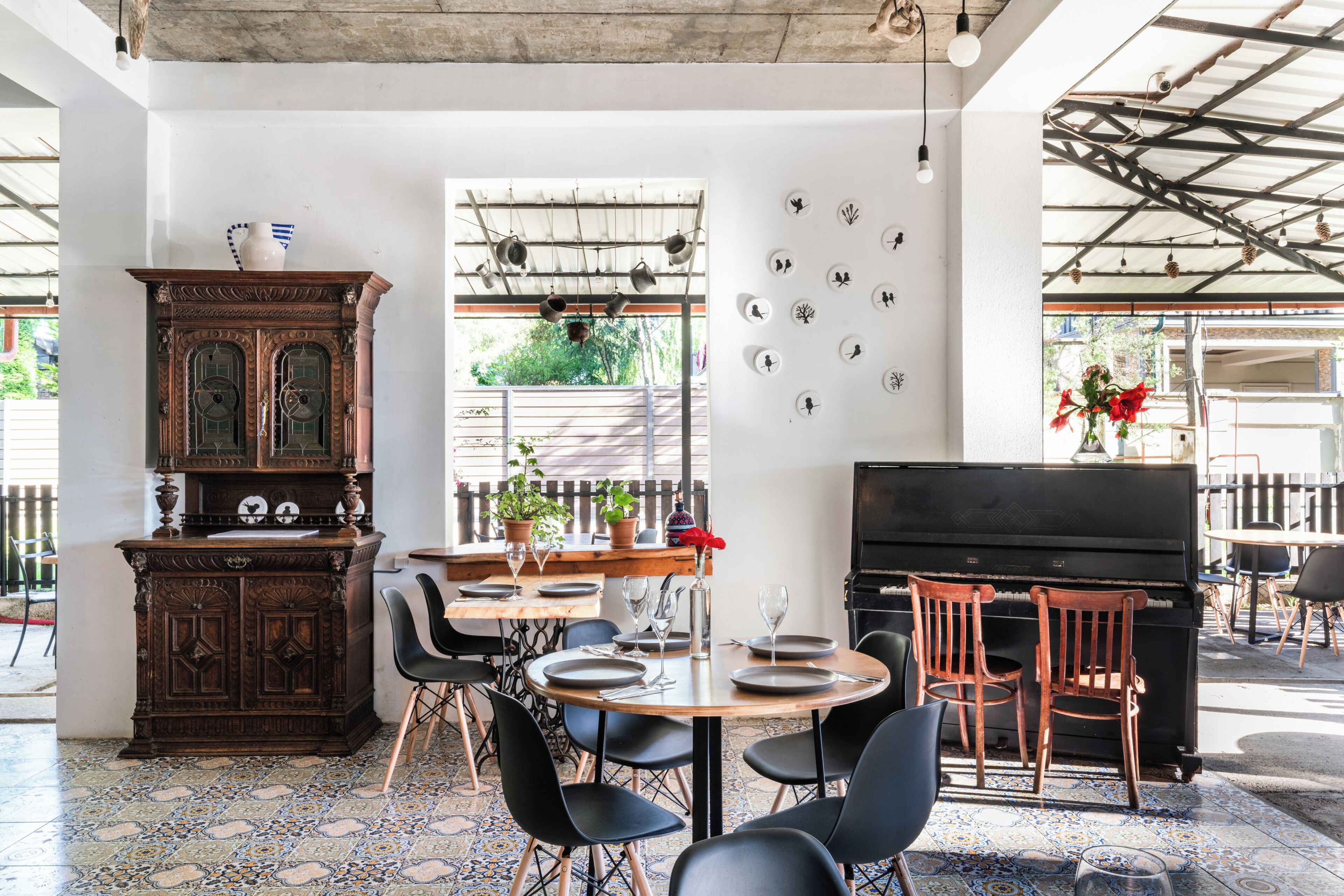 Uma sala de jantar com piano, cadeiras, uma mesa posta para dois e um aparador decorativo.
