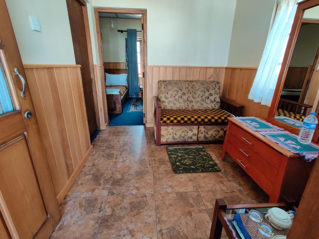 Quarto compacto com cama, sofá, armário de madeira e uma pequena mesa com espelho.