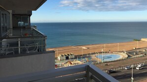 Vista de uma praia com piscina e estrada com carros.