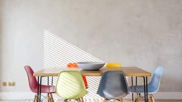 Uma área de refeições com mesa de madeira e cadeiras coloridas.