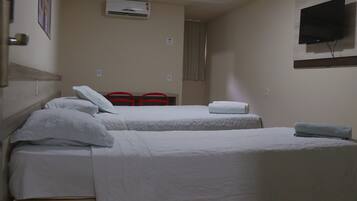Quarto de hotel com duas camas, uma televisão na parede e uma cadeira vermelha.