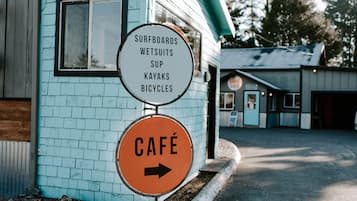 Um edifício com uma placa que anuncia aluguel de pranchas de surf, fatos de neoprene, pranchas de stand-up paddle, caiaques e bicicletas.