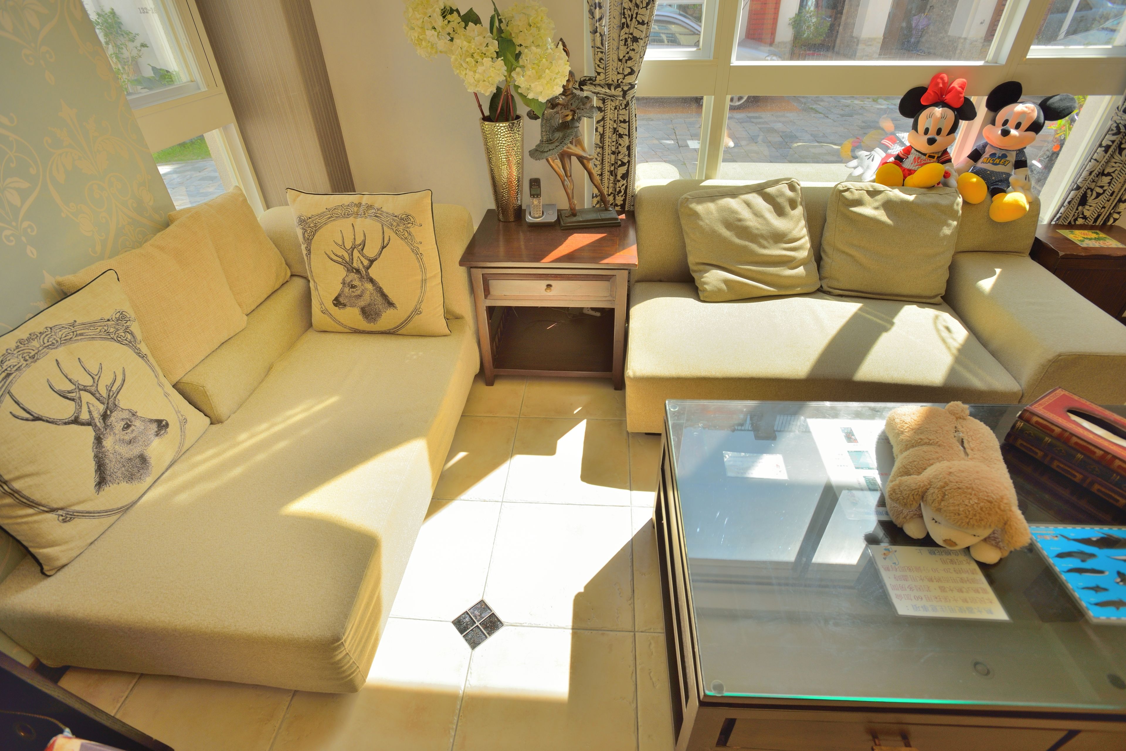 Uma sala de estar aconchegante com um sofá, uma mesa de centro de vidro e almofadas decorativas.