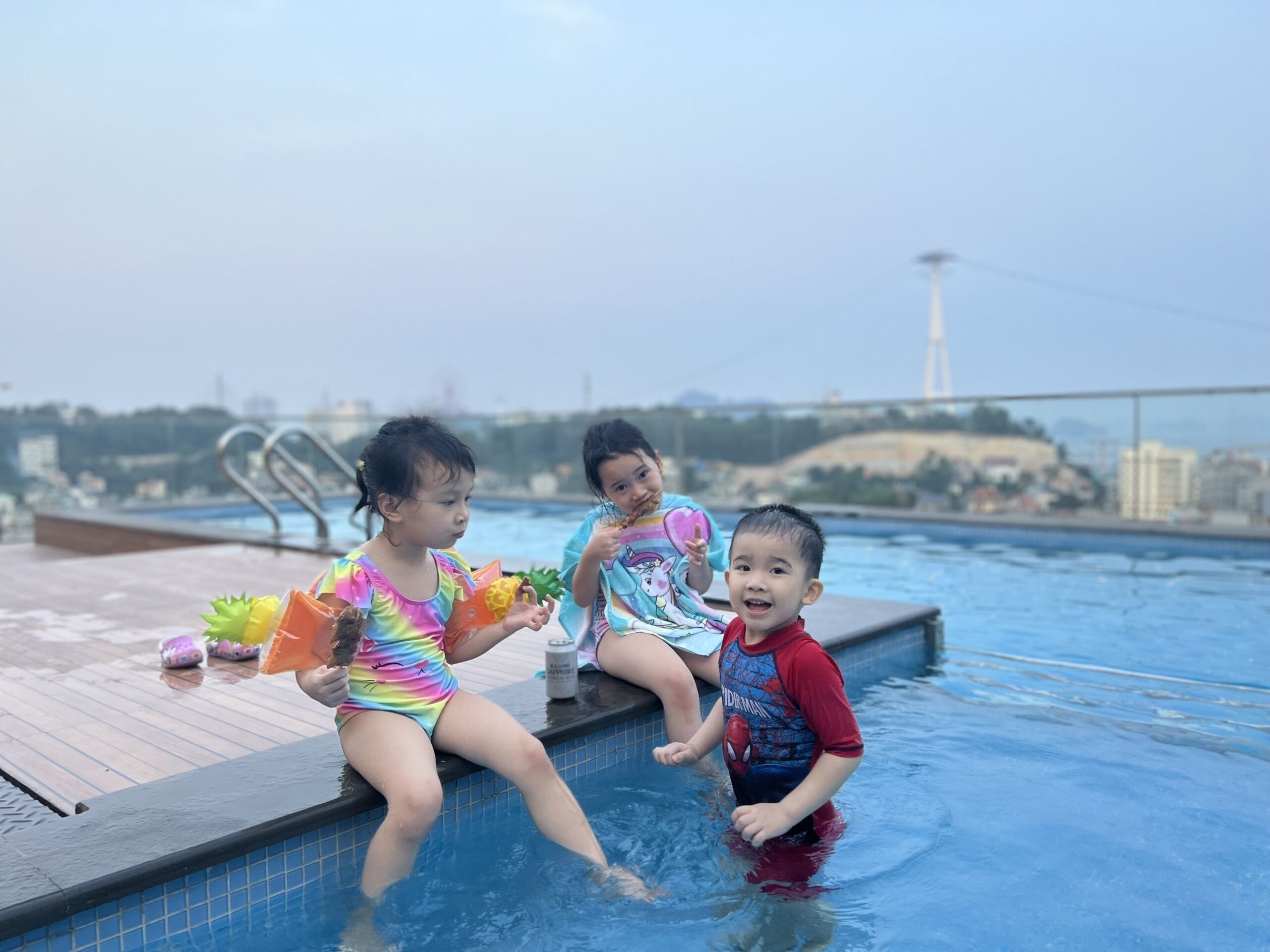 Área da piscina com vista para uma ponte e edifícios ao fundo.