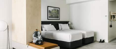 Quarto de hotel moderno com uma cama grande, mesa de cabeceira, guarda-roupa e um quadro na parede.