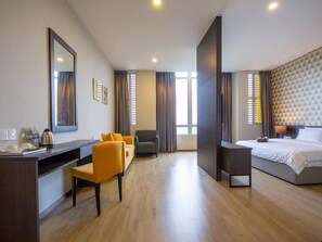 Quarto de hotel moderno com uma cama, escrivaninha, cadeira e sofá.