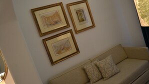 Quarto com sofá bege e três obras de arte emolduradas na parede.