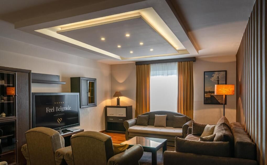 Uma sala de estar moderna com televisão de tela plana, sofá, poltronas, mesa de centro e abajur.