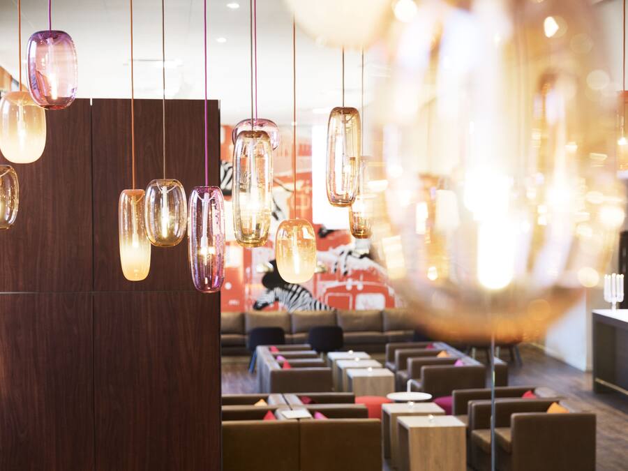 Interior moderno com luminárias pendentes, áreas de estar e divisória de madeira.