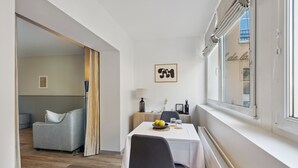 Uma área de refeições compacta com uma mesa, cadeiras e uma pequena mesa lateral com uma tigela de frutas.