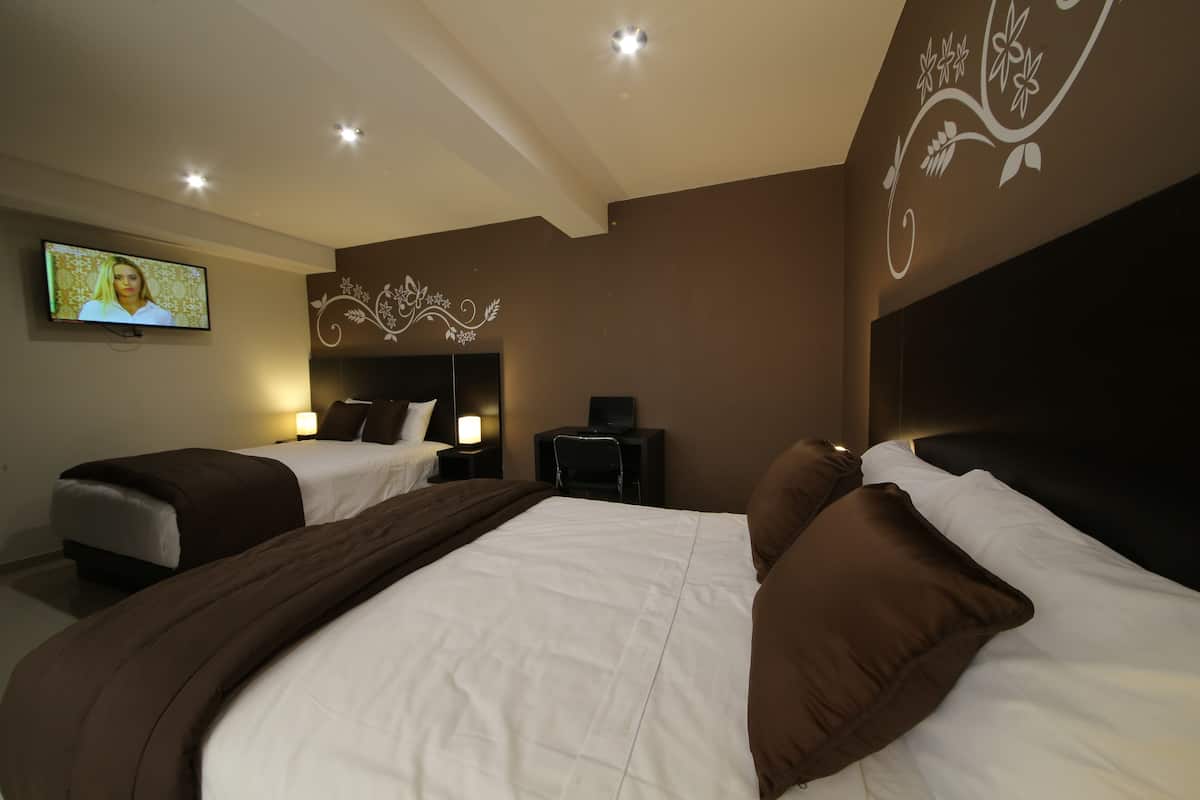 Quarto de hotel com duas camas, uma televisão na parede e decoração nas paredes.