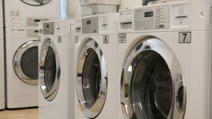 Uma fileira de máquinas de lavar industriais, numeradas 5, 6 e 7, em uma instalação.