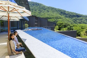 Piscina com vista para uma montanha e um edifício moderno ao fundo.