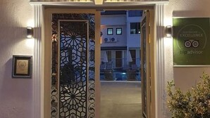 Entrada de hotel com um portão decorativo, um certificado de excelência e um vaso de planta.
