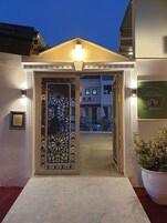 Entrada de hotel com um portão decorativo, um certificado de excelência e um vaso de planta.