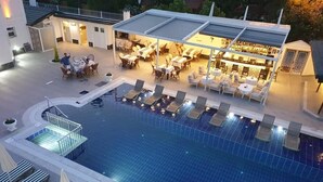 Piscina no terraço com espreguiçadeiras e um bar.