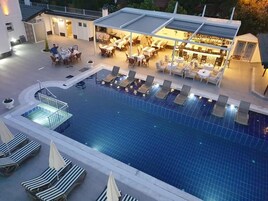 Piscina no terraço com espreguiçadeiras e um bar.