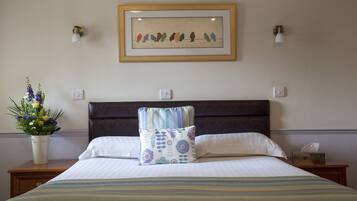 Cama bem arrumada com colcha listrada, almofada decorativa e quadro na parede acima.