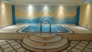 Uma grande piscina coberta com piso de azulejos e um mural na parede.