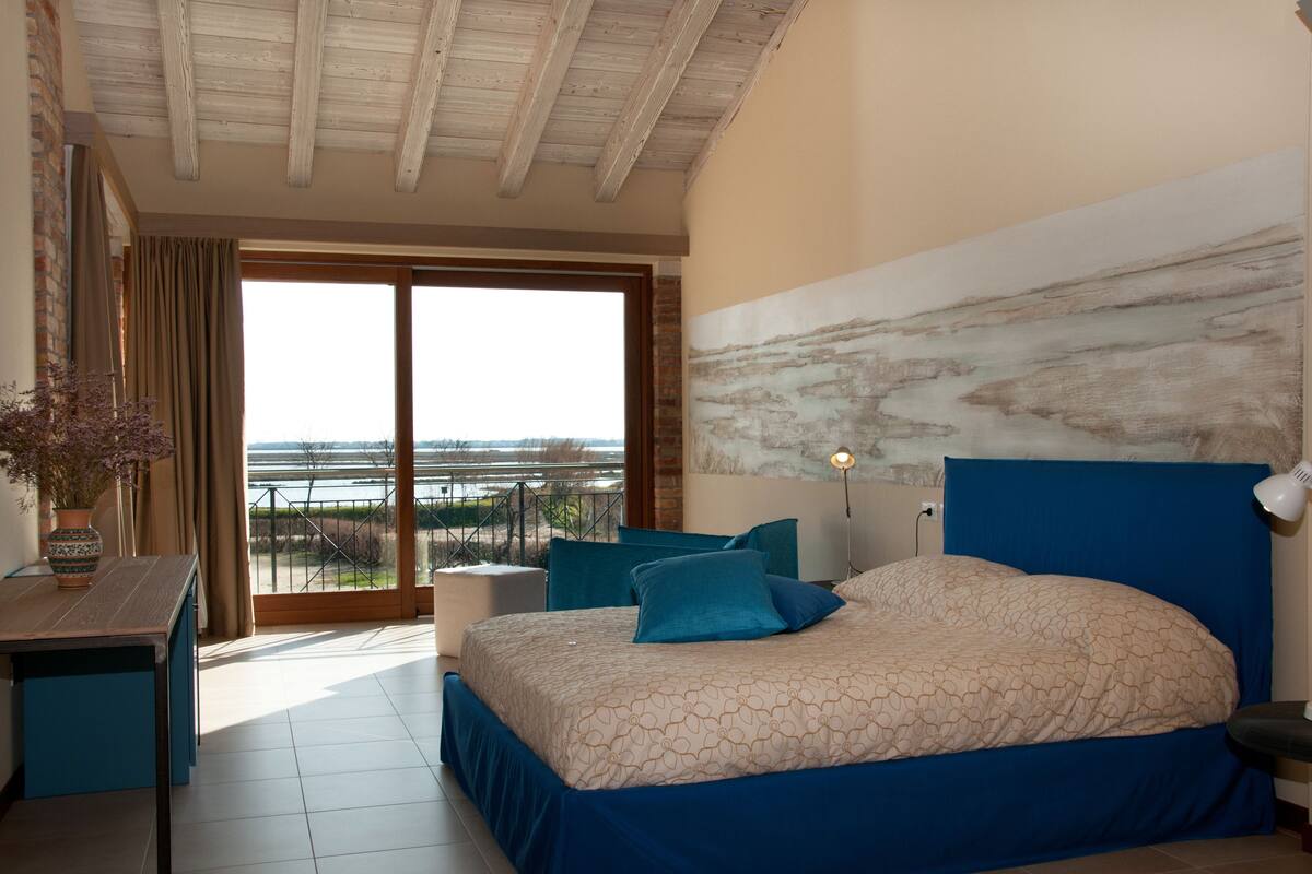 Quarto com cama grande, escrivaninha e vista para o exterior.