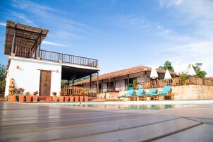 Uma área na piscina com espreguiçadeiras e um edifício com varanda.