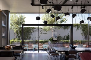 Um espaço de refeições interno com grandes janelas, iluminação moderna e área de estar ao ar livre.