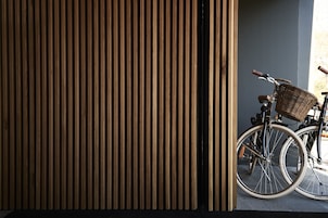 Parede de ripas de madeira com uma bicicleta encostada.