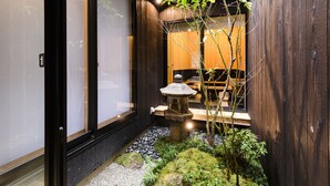 Um jardim japonês tradicional com um farol de pedra, rochas cobertas de musgo e uma cerca de madeira.