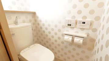 Um banheiro pequeno e moderno, com vaso sanitário, pia e rolo de papel higiênico.