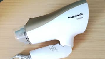 Um secador de cabelo Panasonic com corpo branco e parte superior cinza, sobre uma superfície de madeira.