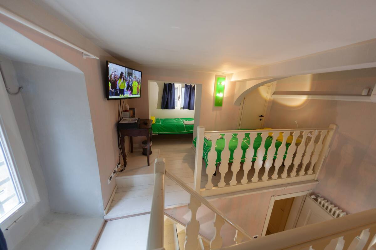 Quarto com cama, televisão, janela e escada.