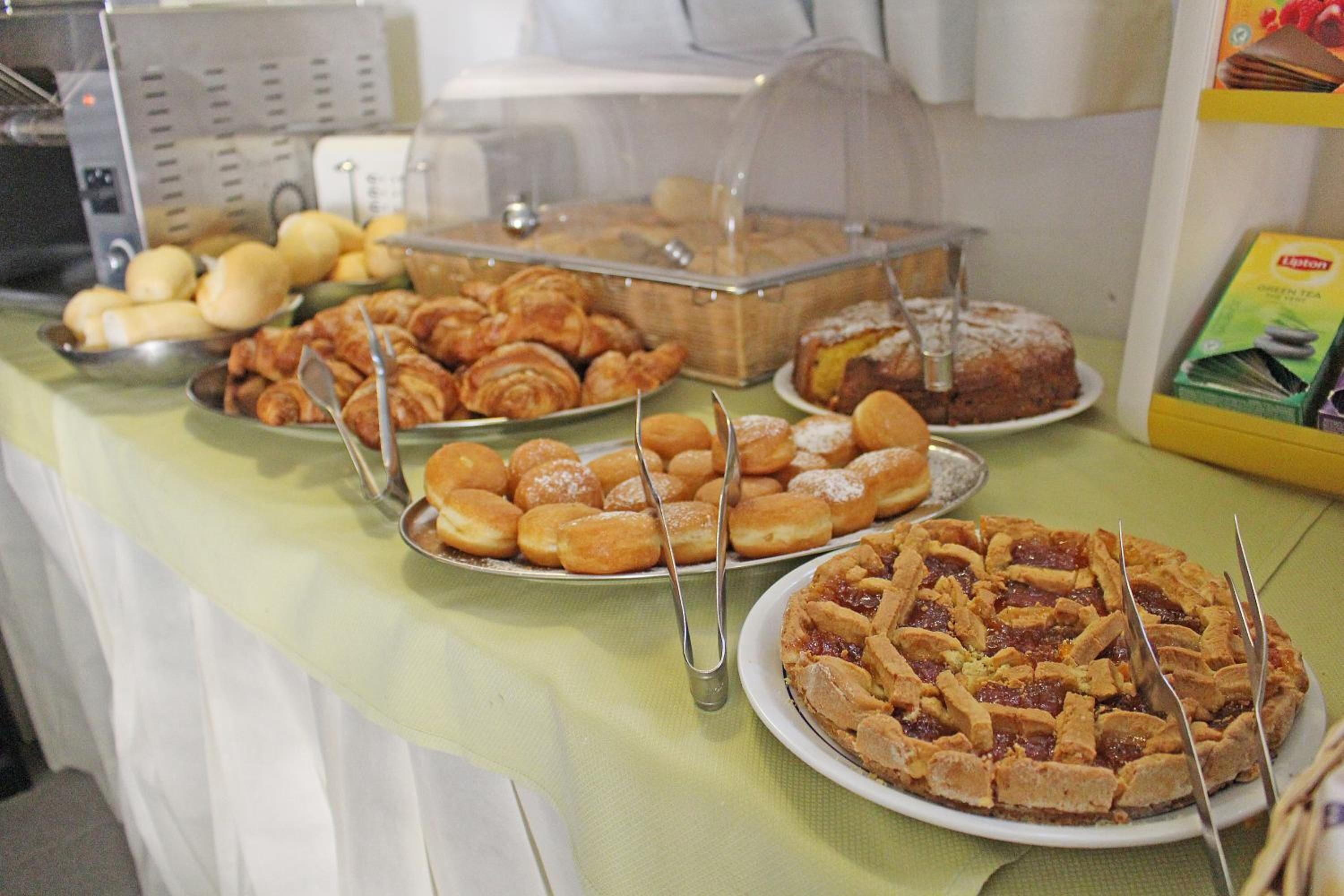 Uma mesa de buffet com diversos produtos de panificação, incluindo doces, tortas e pão.