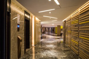 Corredor de hotel com elevadores, um sinal de diretório e parede com padrão.