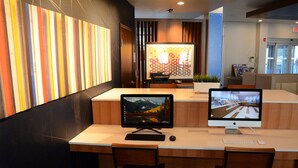 Balcão de recepção com dois monitores, teclado e rato. Há duas cadeiras em frente ao balcão.