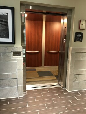 Um elevador com portas de madeira e parede de mármore.