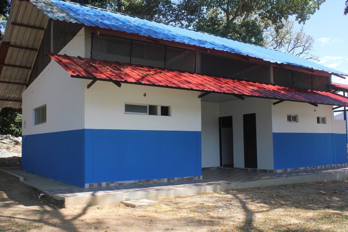 Um edifício de dois andares com fachada azul e branca, telhado vermelho e um pequeno alpendre.