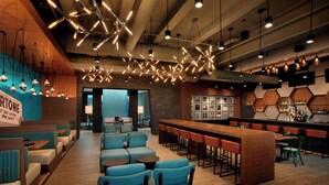 Uma área de bar moderna com assentos azuis, balcão de madeira e iluminação pendente.