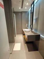 Casa de banho moderna com um espelho grande, uma pia e zona de duche.