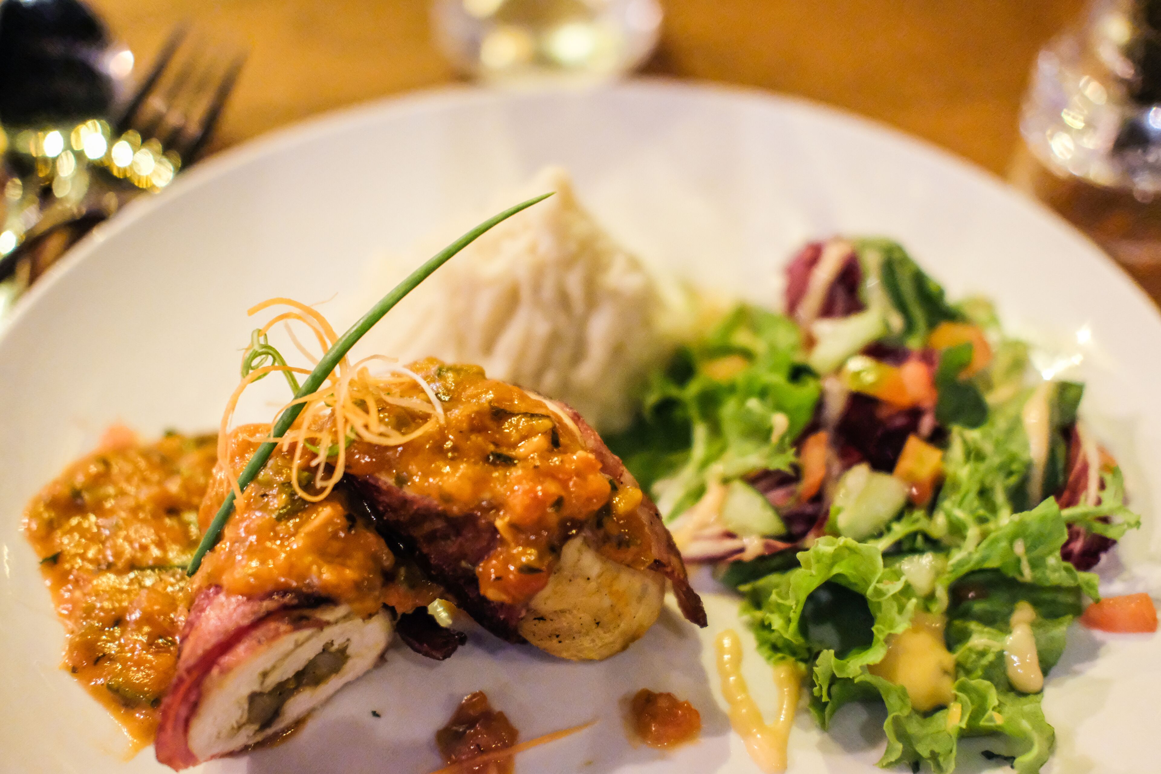 Prato com salada e carne acompanhada de molho.