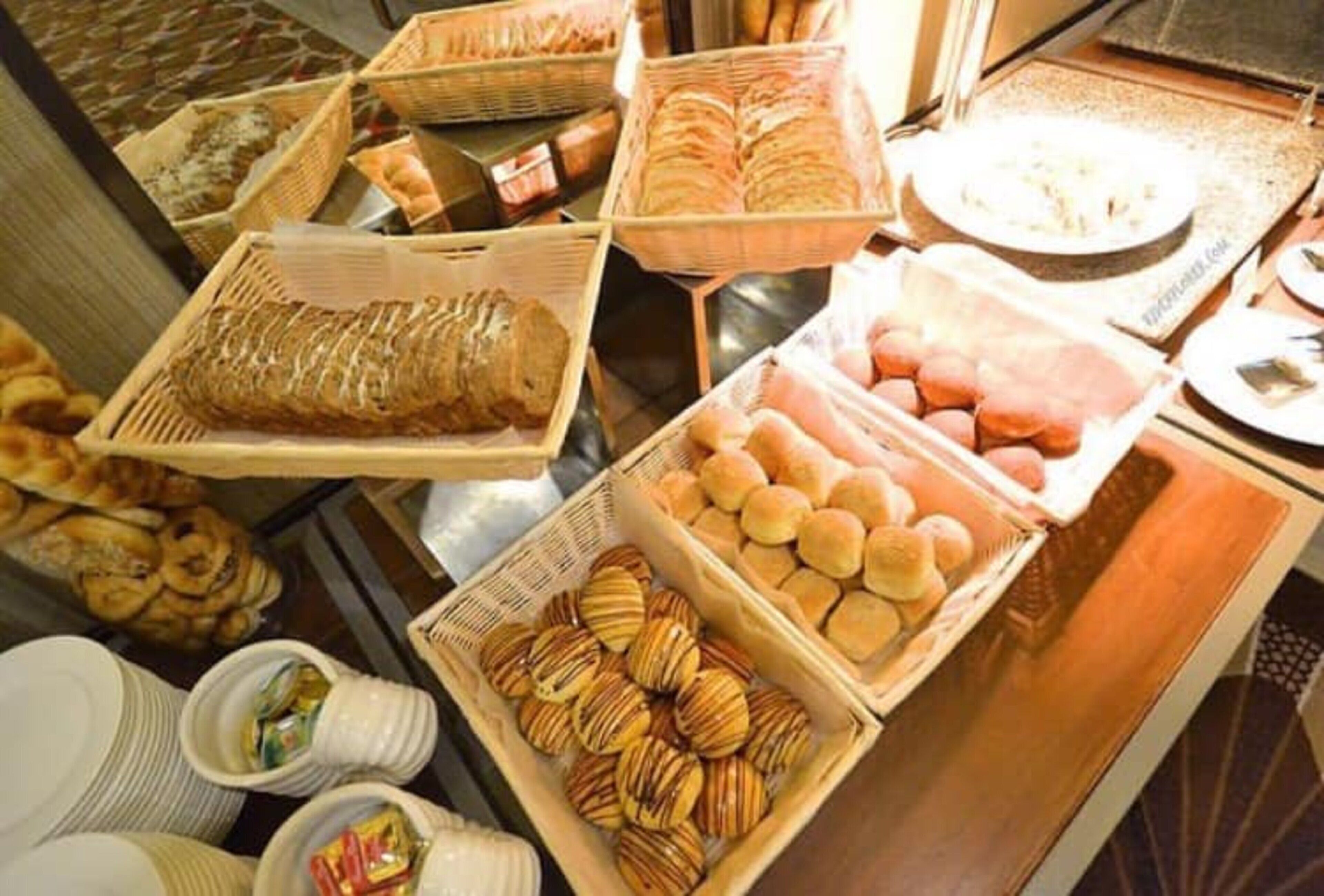 Diversos produtos de panificação expostos em cestas, incluindo pão, doces e pãezinhos.