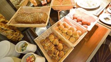 Diversos produtos de panificação expostos em cestas, incluindo pão, doces e pãezinhos.