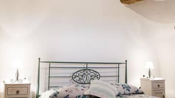 Quarto com estrutura de cama de metal, viga de teto de madeira e parede branca.