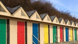 Uma fileira de cabanas individuais coloridas, com uma escada que leva à entrada.